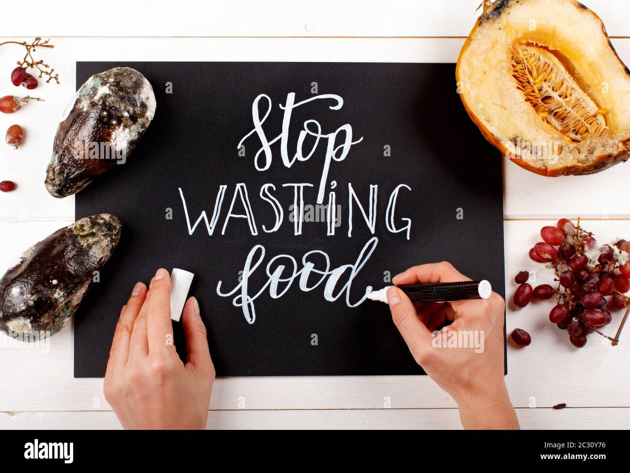 Woman writing on a small chalkboard Stop wasting food lettering top ...