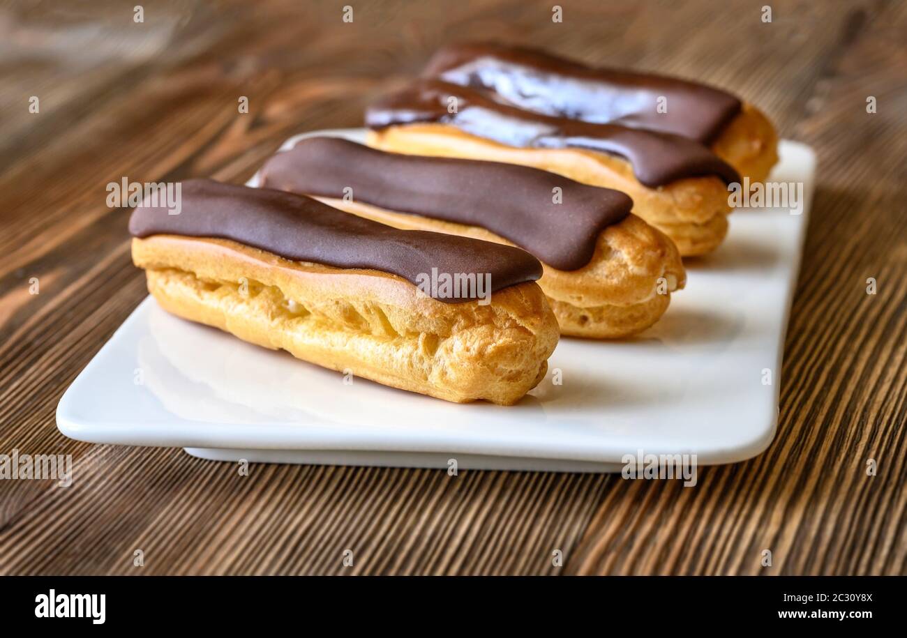 Eclairs with chocolate topping on serving plate Stock Photo - Alamy