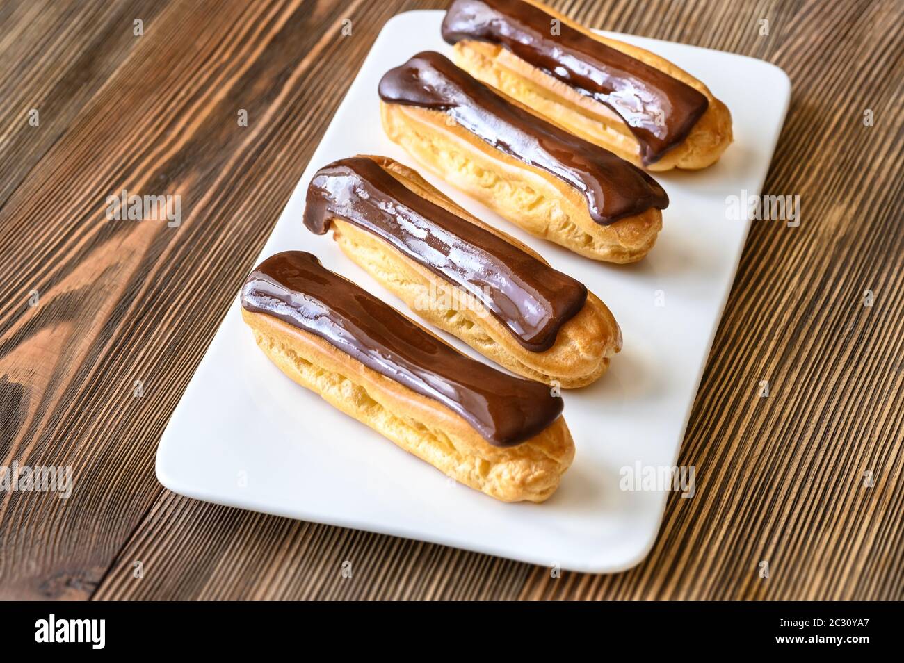 Eclairs with chocolate topping on serving plate Stock Photo - Alamy