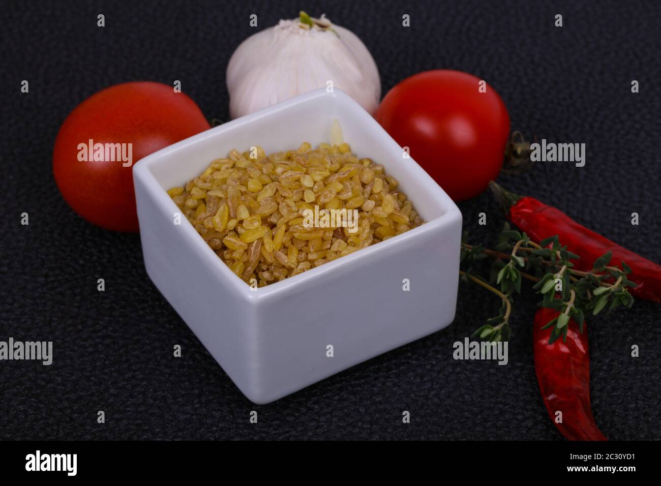 Raw golden bulgur in the bowl with tomatoes and garlic Stock Photo - Alamy