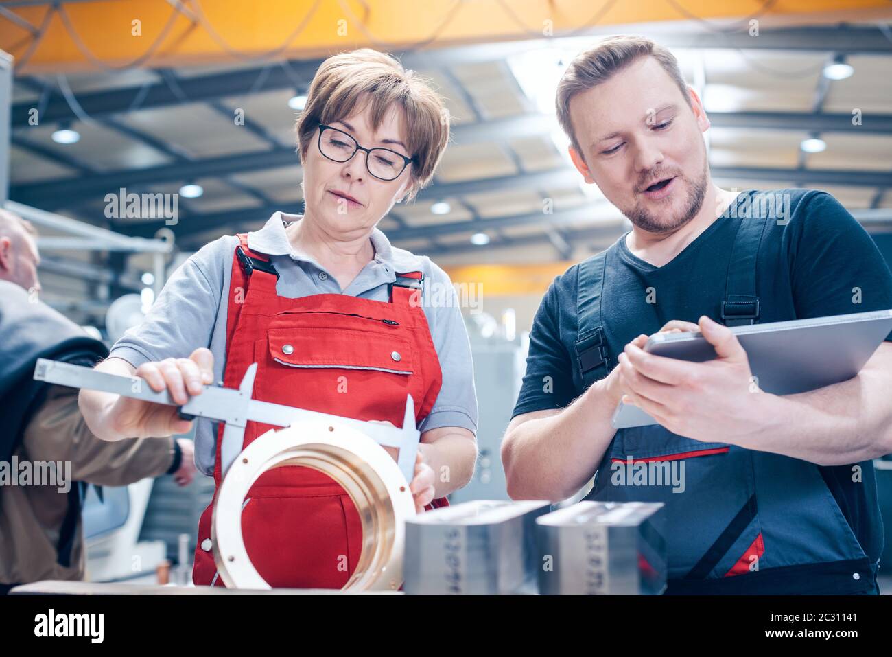 Workers measuring a metal workpiece with gauge Stock Photo - Alamy