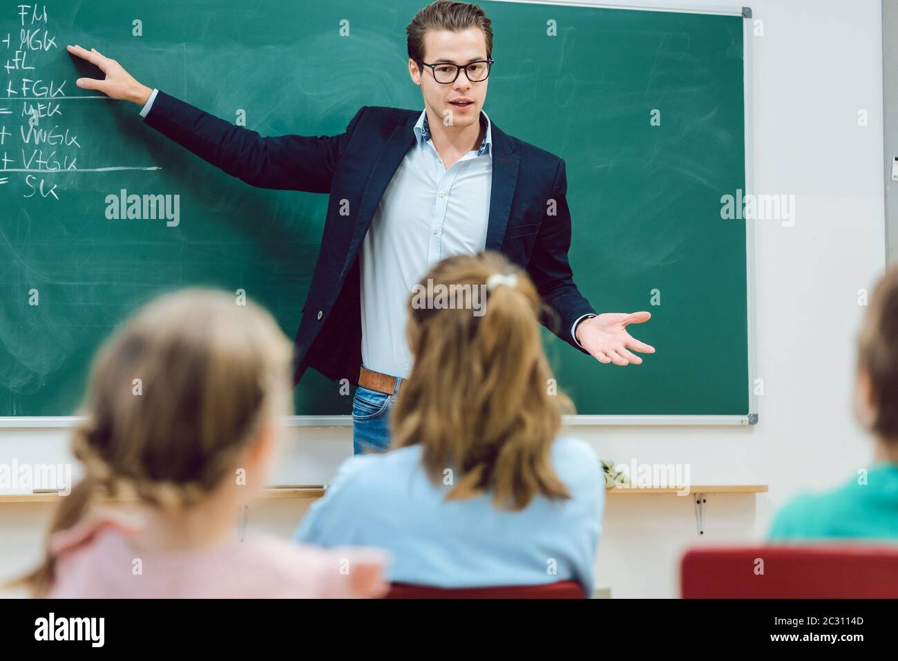 Teacher standing in front of students in school class explaining ...