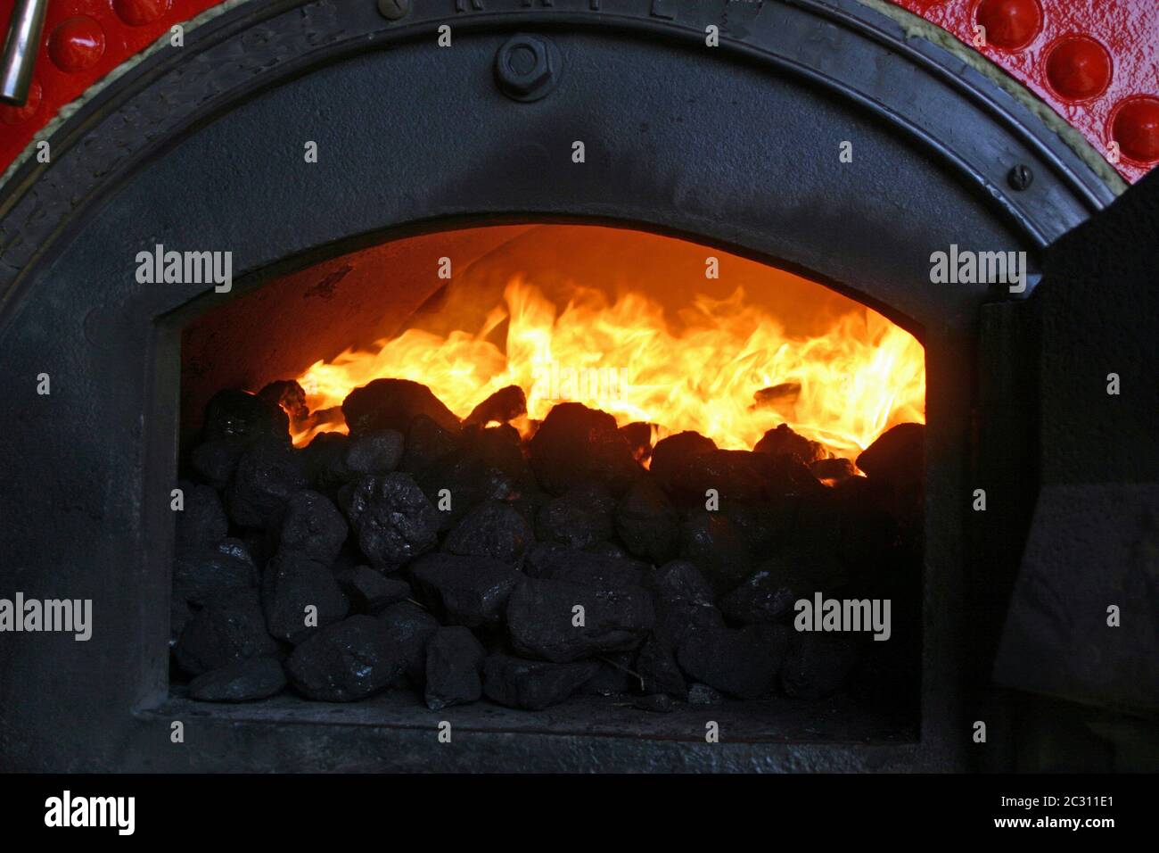 Burning coal with bright flames and smoke in the boiler of a steam ...