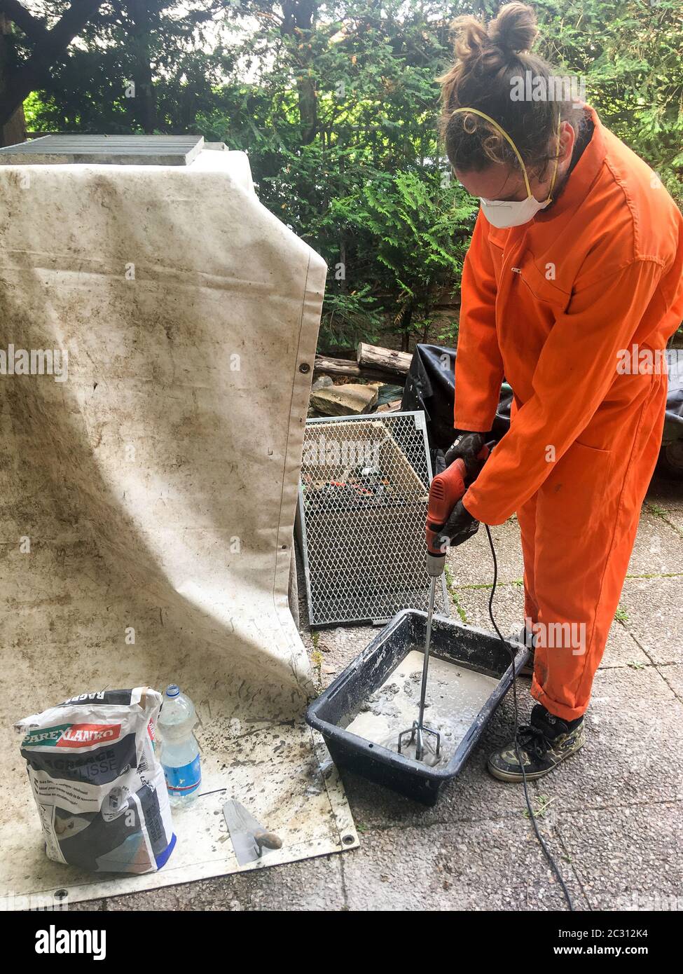 Young worker wearing orange suit at work on a restoring site, Bron ...