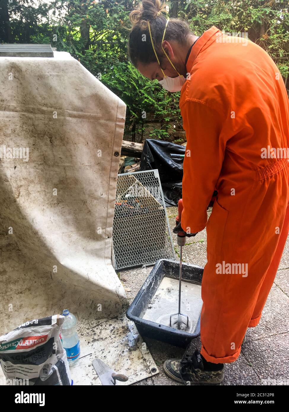 Young worker wearing orange suit at work on a restoring site, Bron ...