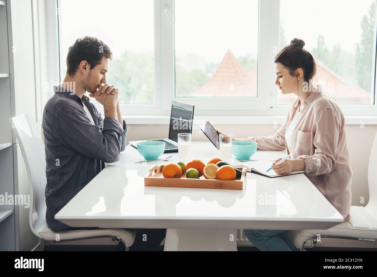 Side view photo of a caucasian couple sitting at the table and eating ...