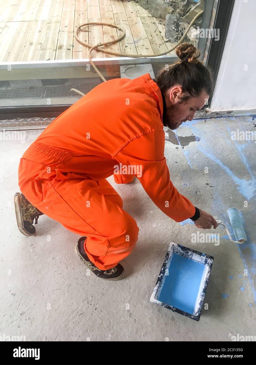 Young worker wearing orange suit at work on a restoring site, Bron ...
