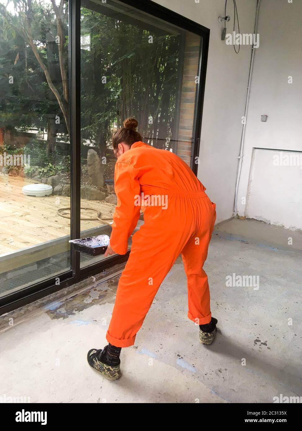 Young worker wearing orange suit at work on a restoring site, Bron ...