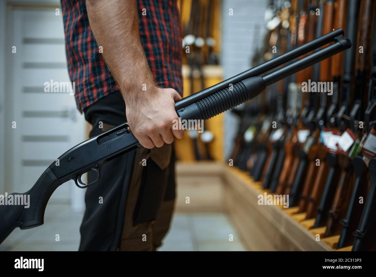 Male person with rifle at showcase in gun shop. Euqipment for hunters ...