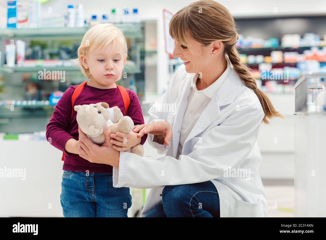 Pharmacist woman with child customer and her plush toy in pharmacy ...