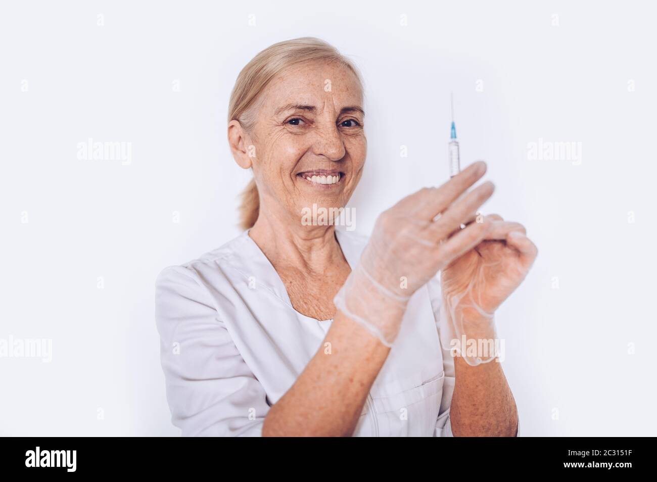 Elderly happy mature woman doctor or nurse with syringe in a white ...
