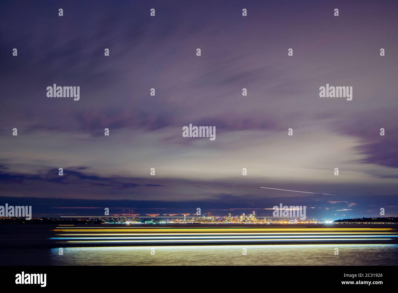 Seattle waterfront skyline at sunset with light trails of ferry passing ...