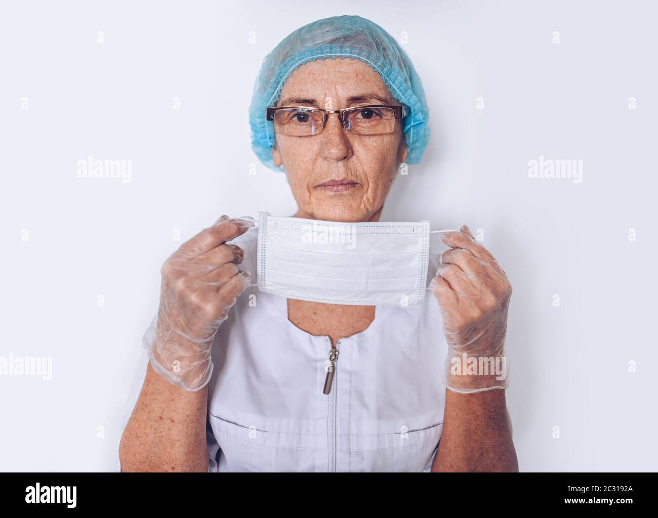 Elderly mature woman doctor or nurse in a white medical coat, gloves ...