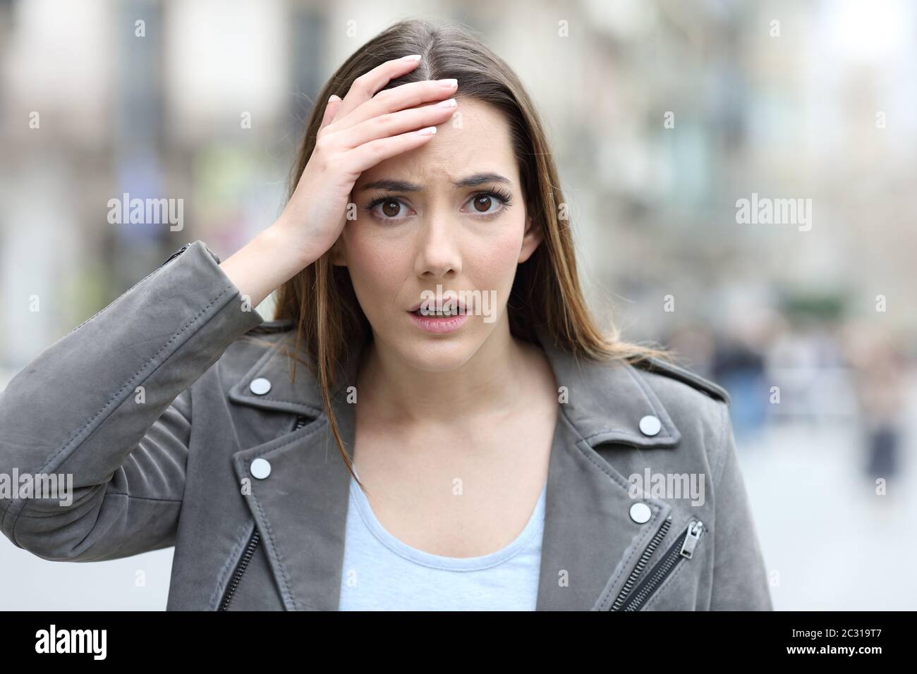 Front view portrait of a worried woman looking at camera with hand on ...