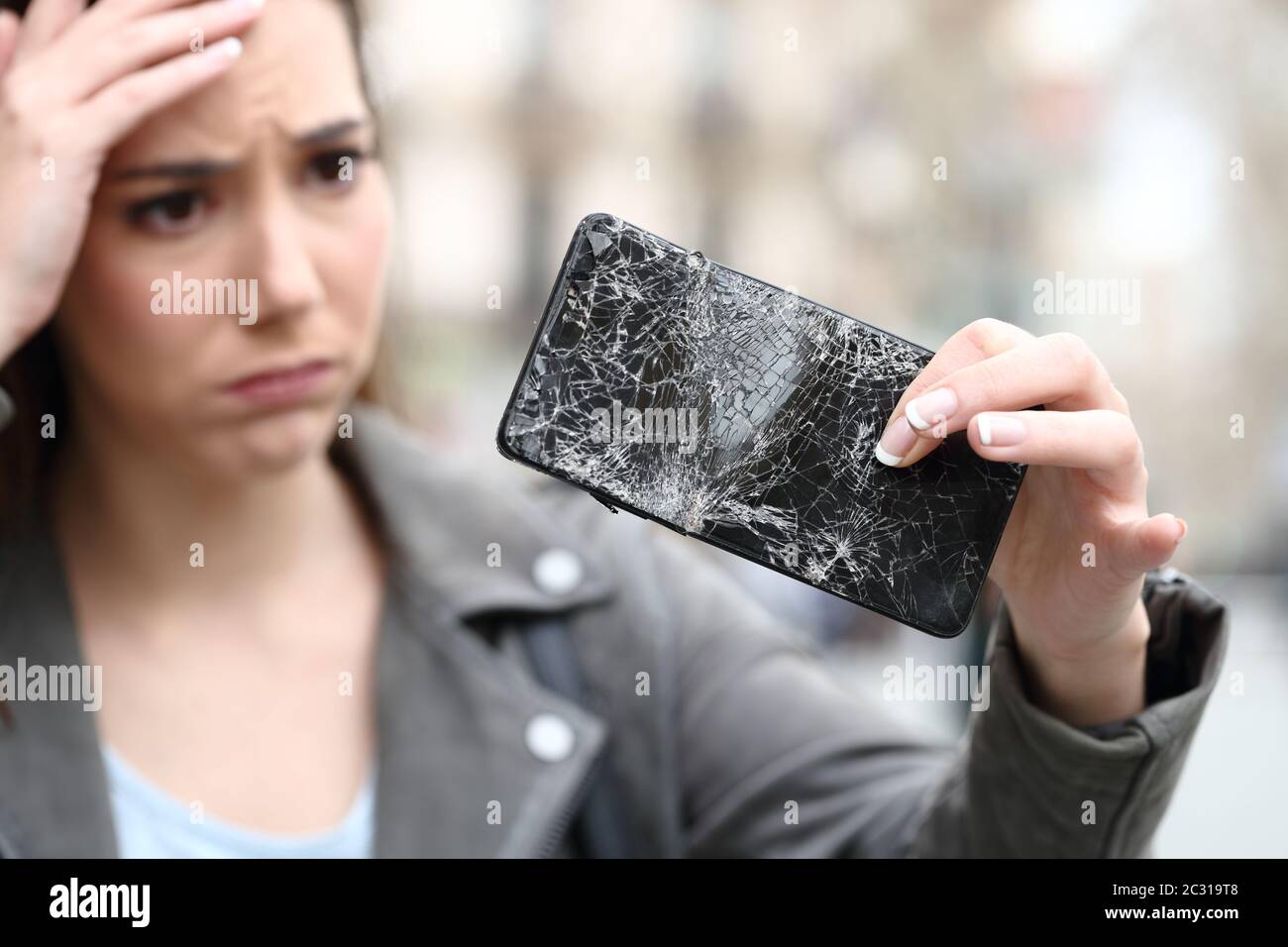 Close up of a worried woman hand holding her broken smart phone with ...