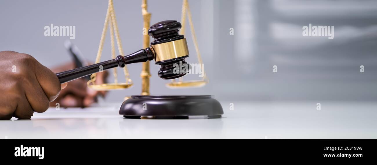 Close-up Of A Judge Hands Writing On Document With Gavel And Scale At ...