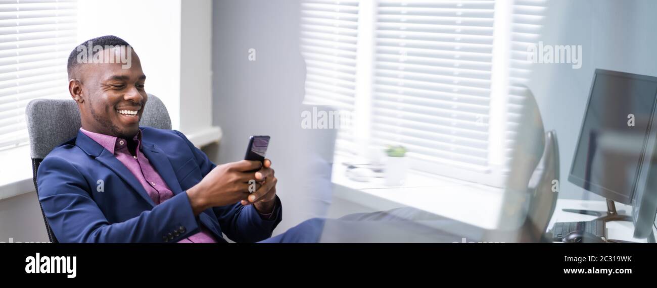 Lazy Man Using Phone At Work Desk Instead Of Working Stock Photo - Alamy