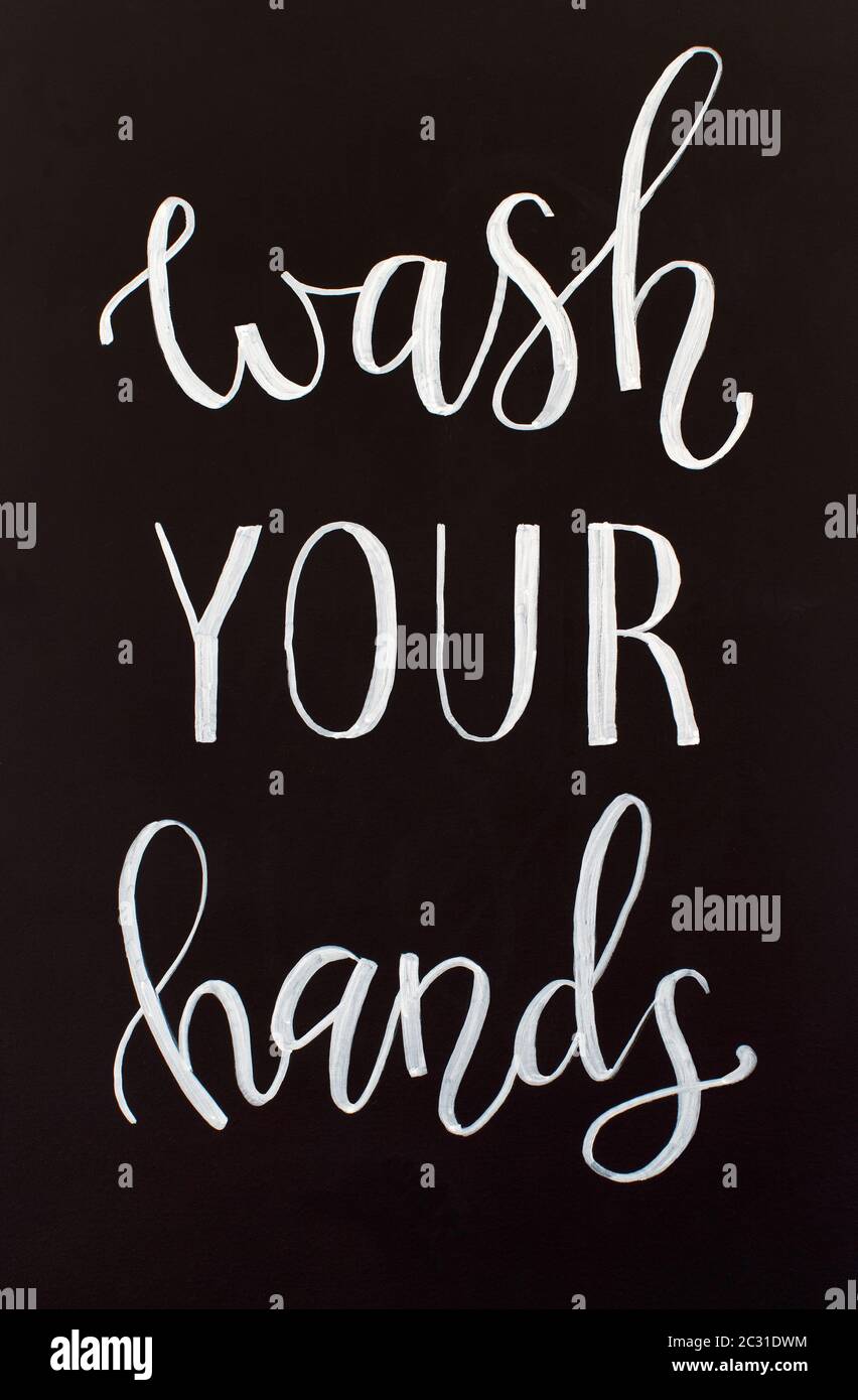 Chalk inscription WASH YOUR HANDS on a black chalkboard. Handwritten ...