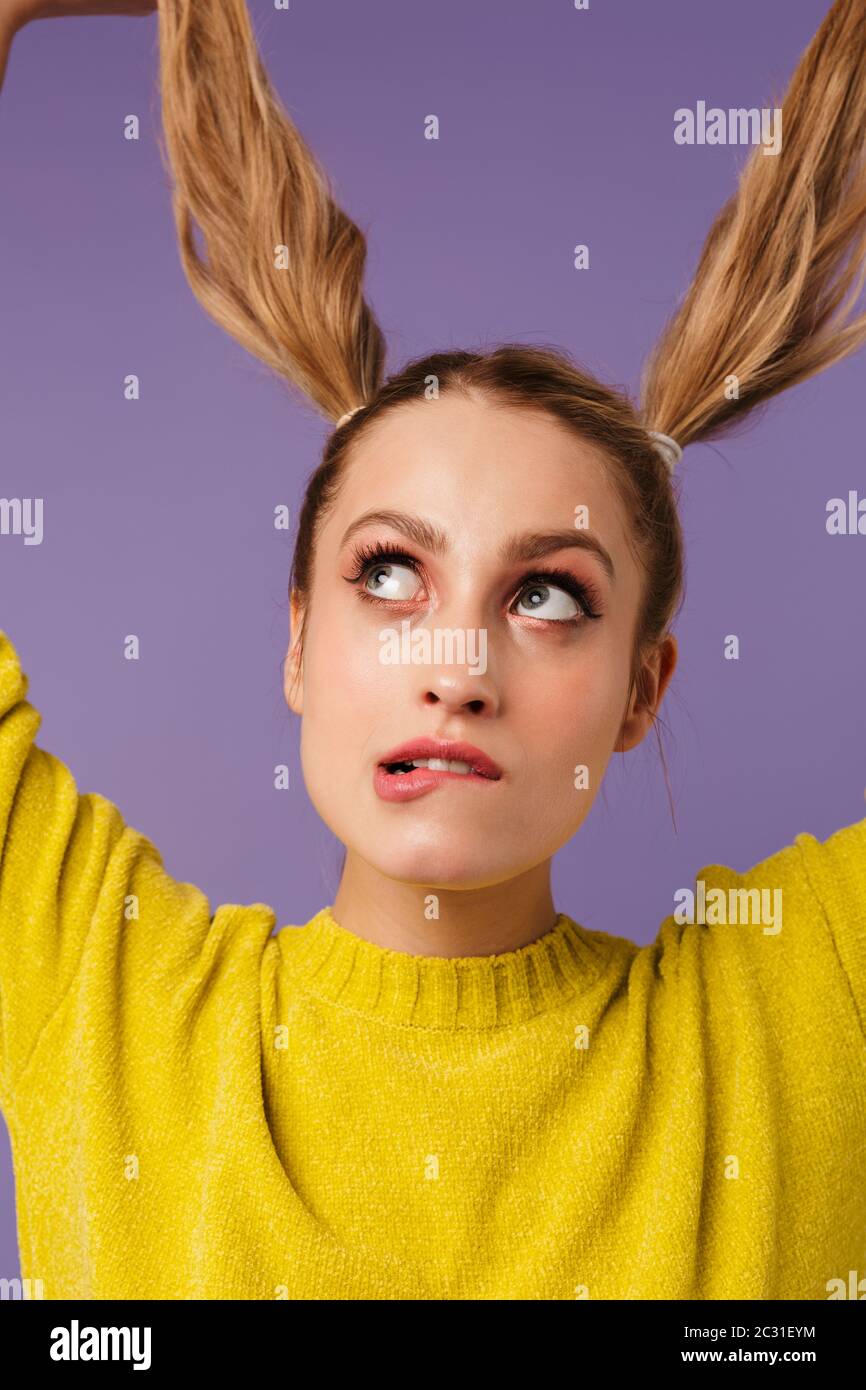 Image of thinking pretty woman having fun with two tails isolated over ...