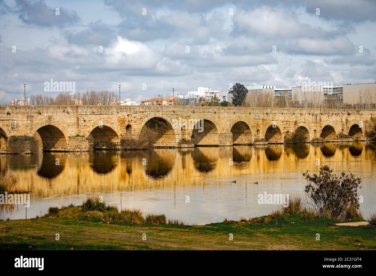 Roman bridge with its arches are reflected on the river on an autumn ...