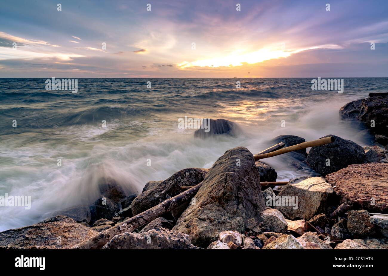 Ocean water splash on rock beach with beautiful sunset sky and clouds ...