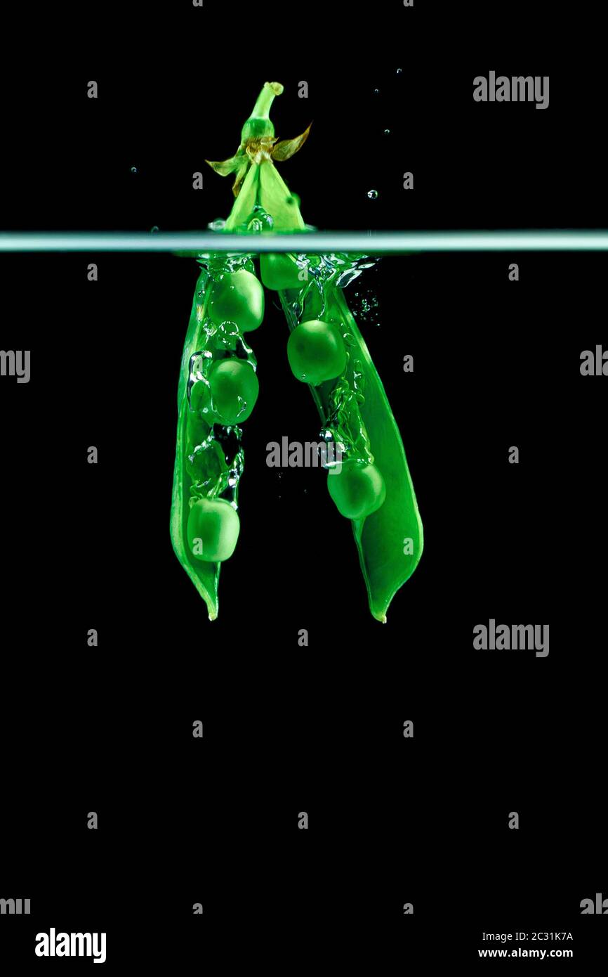 Fresh pea dropped into a water on dark background isolate Stock Photo ...