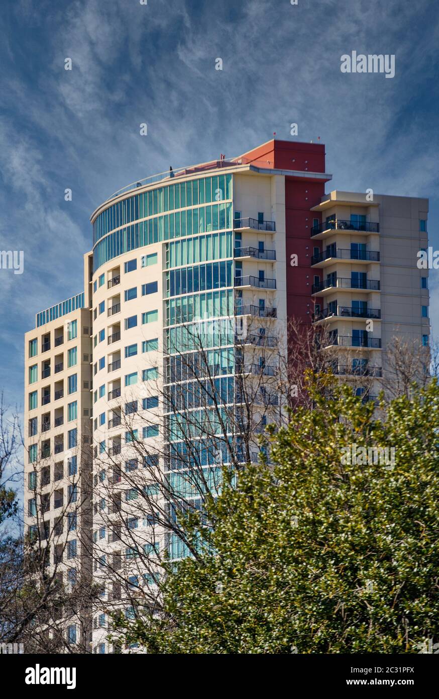 A red, white and blue condominium tower rising into clear blue skies ...