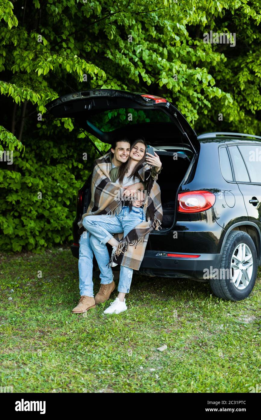 Young people take selfie on phone in car trunk and sunset time Stock ...