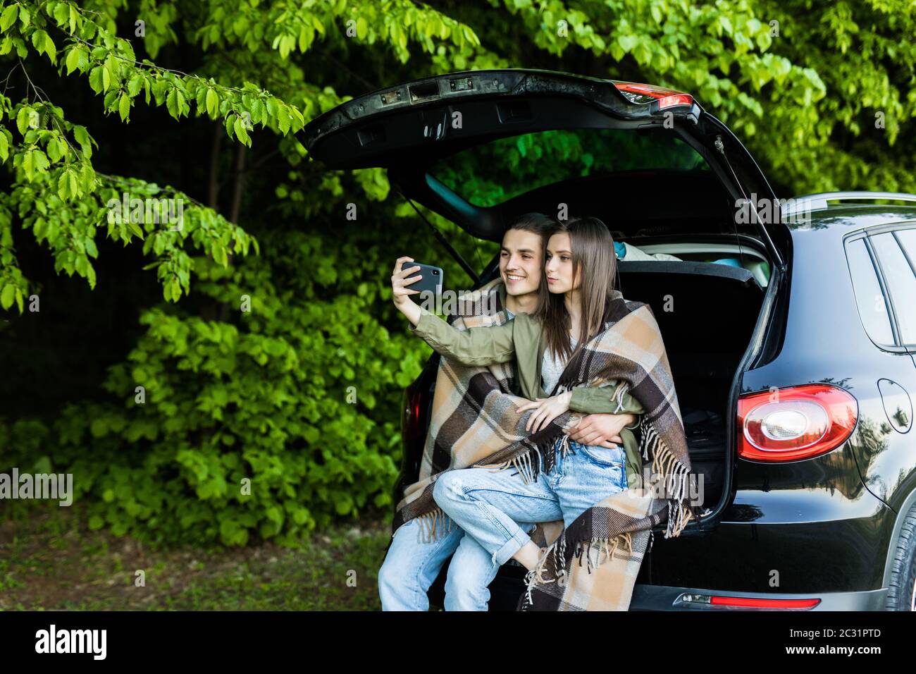 Young people take selfie on phone in car trunk and sunset time Stock ...