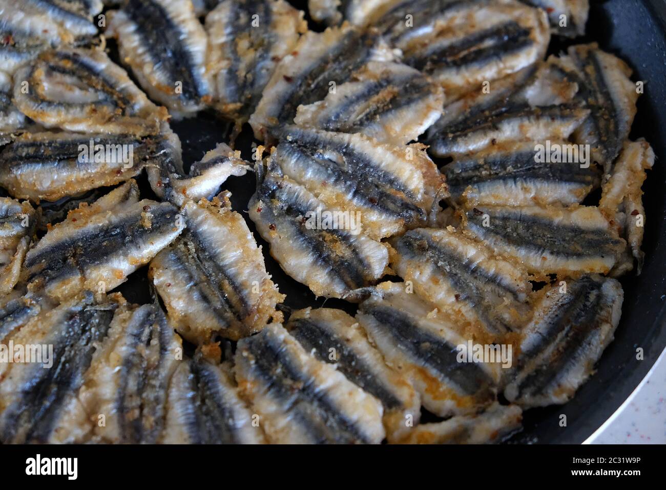 anchovy fish cooked on a stove, cooking anchovy in a pan, anchovy in a ...