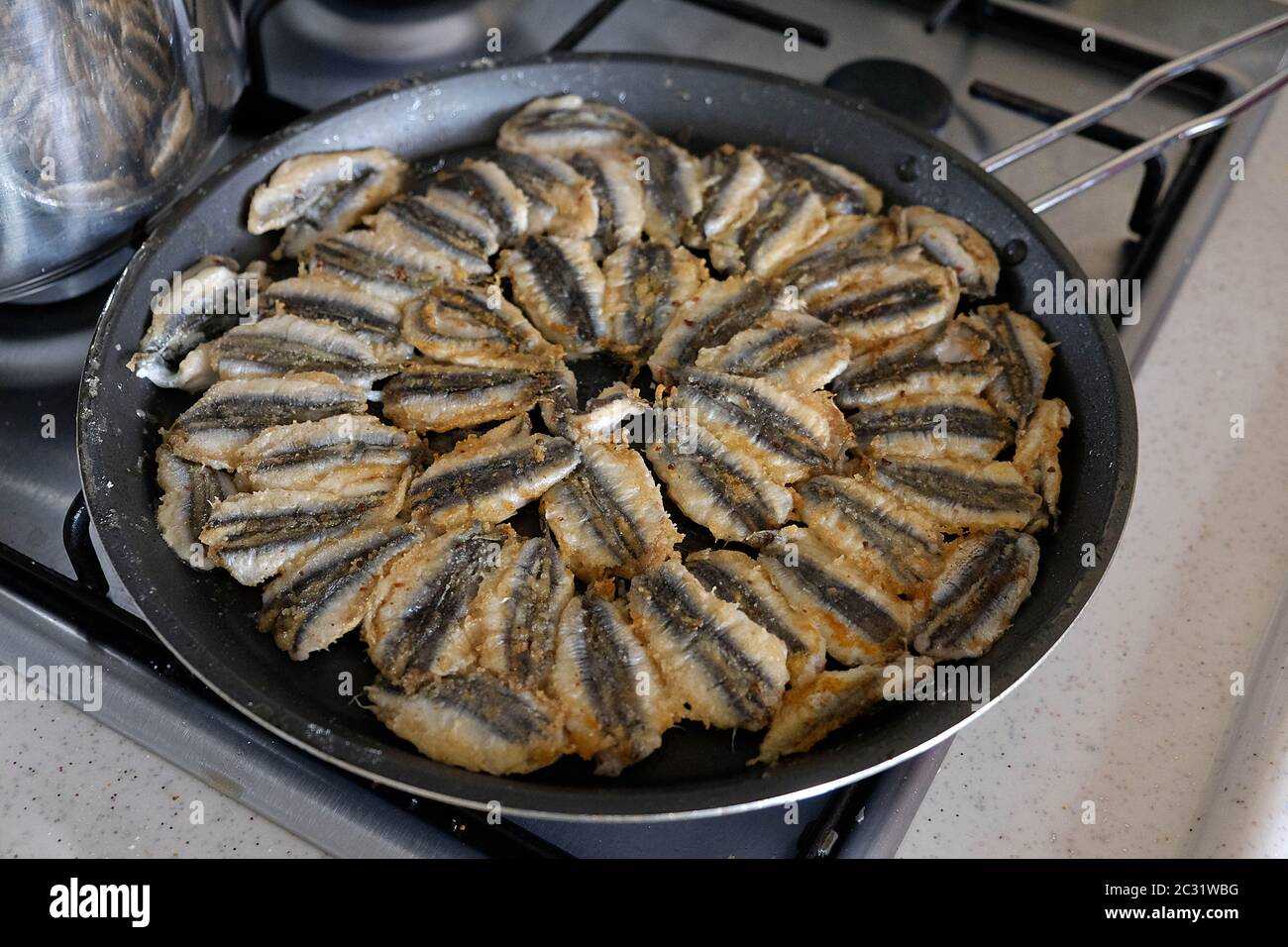 anchovy fish cooked on a stove, cooking anchovy in a pan, anchovy in a ...