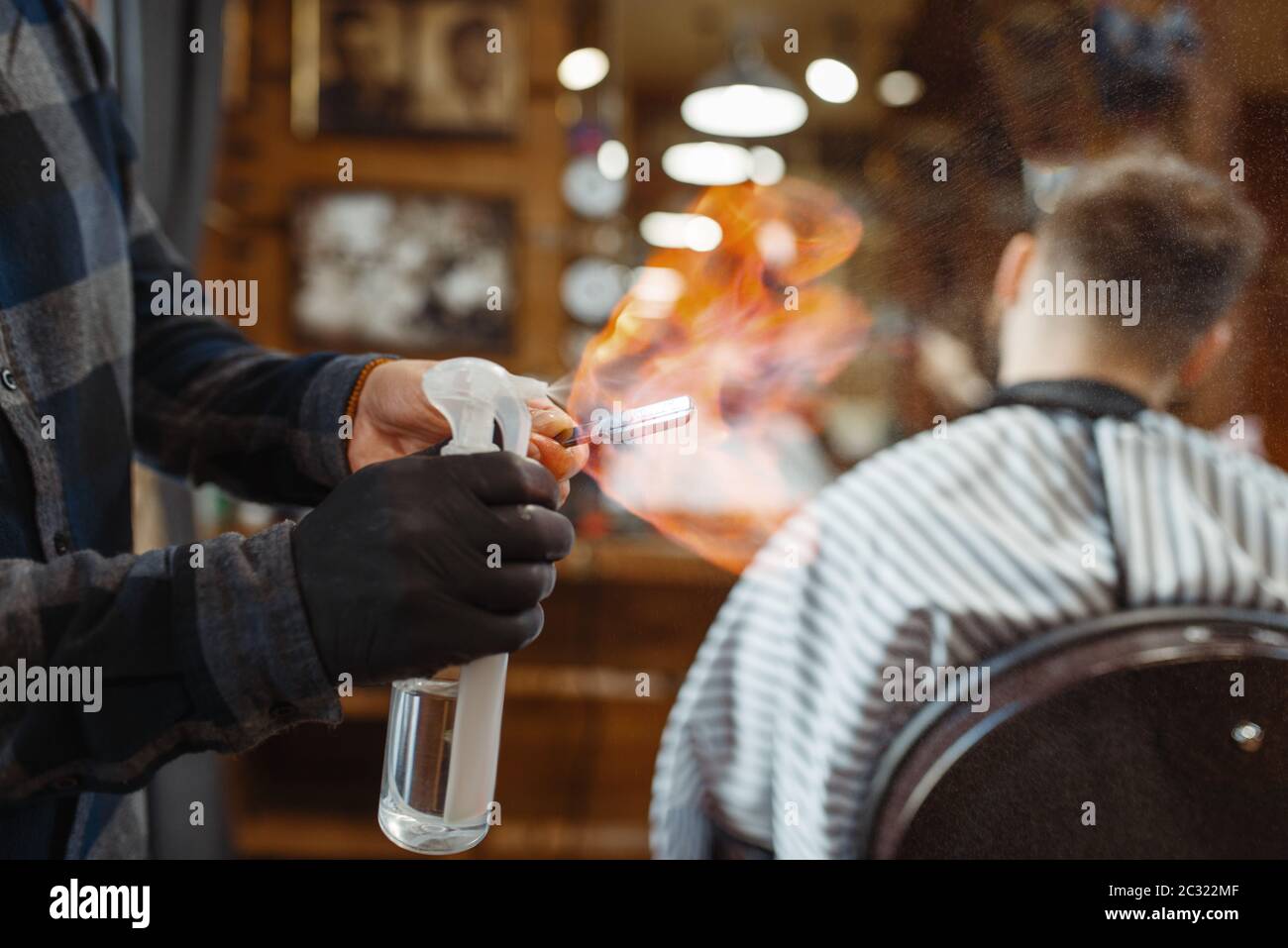 Barber processes the blade with fire, customer sitting in chair ...