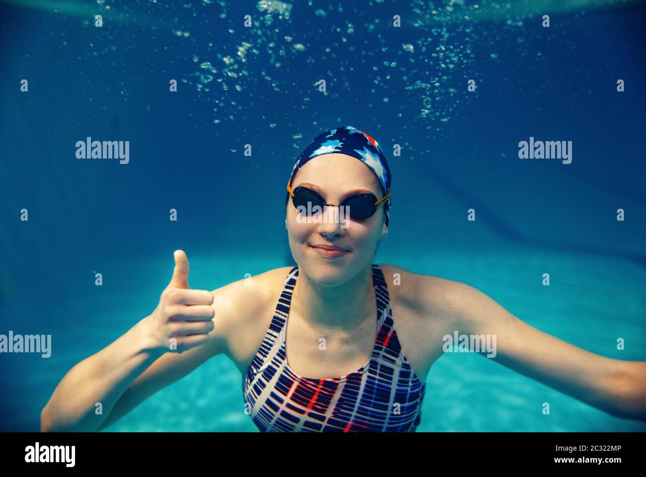 Female Swimmer In Swimsuit Swimming Cap And Glasses Shows Thumbs Up
