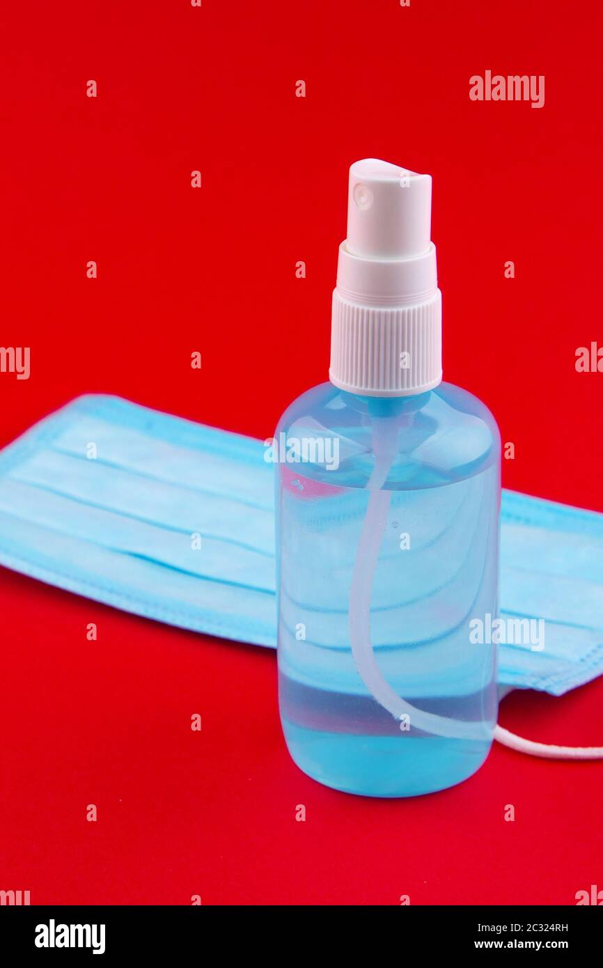 Medical mask and sanitizer on a red background. Antibacterial spray for ...
