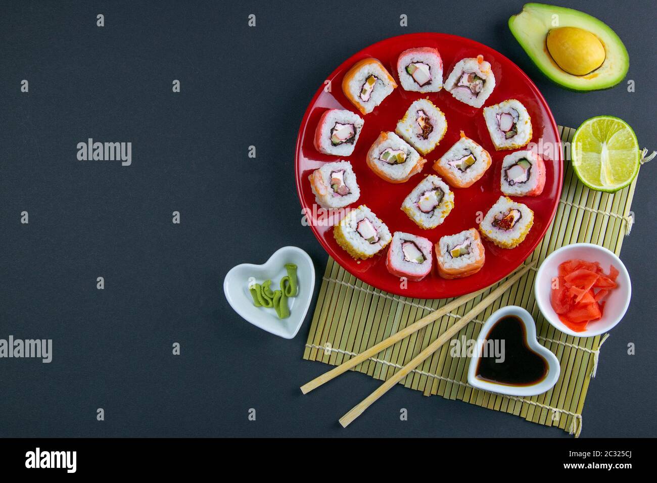 Red plate with sushi, filled with rolls of different kinds, next to ...
