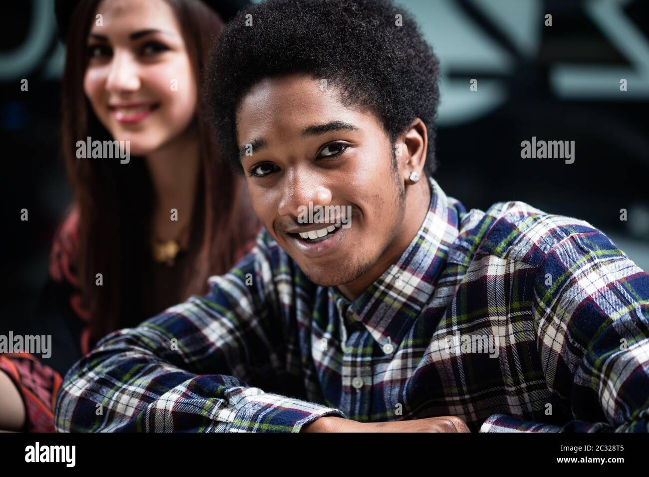 Portrait of an african teenage boy in plaid shirt and his girlfriend in the background Stock ...