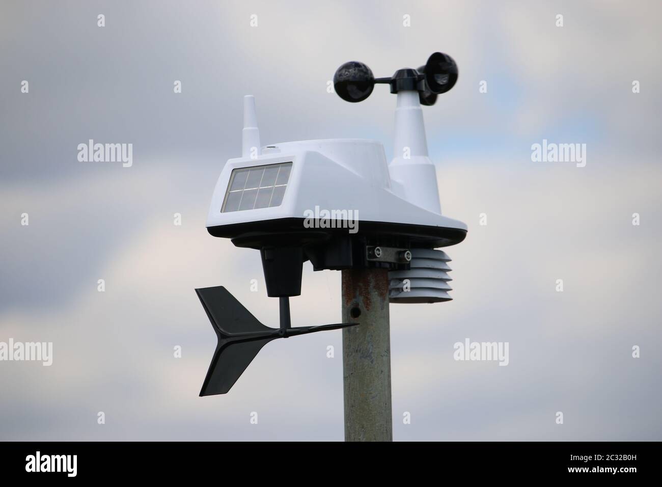 Light grey weather station on a pole topped by a wind speed indicator ...