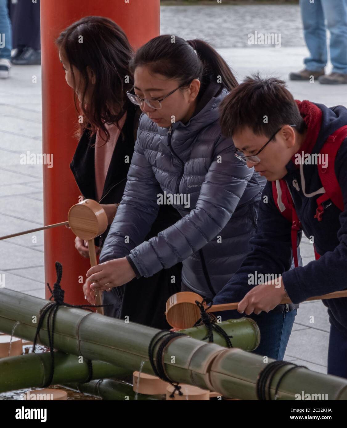 Tourist performing water cleansing ritual before entering Fushimi Inari ...