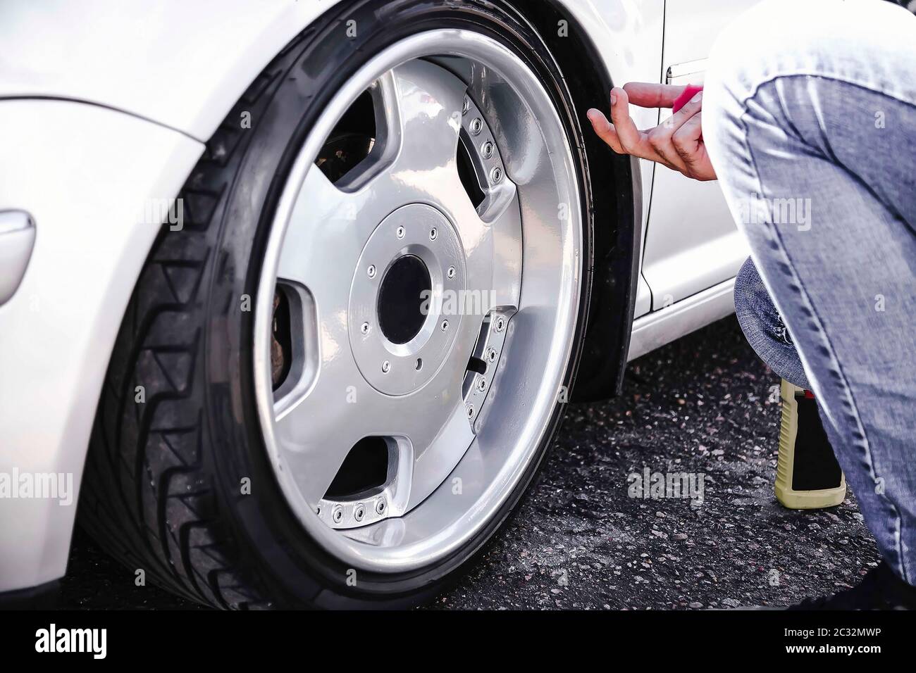 A man cleans the wheels of his car. Dropped silver car on air ...