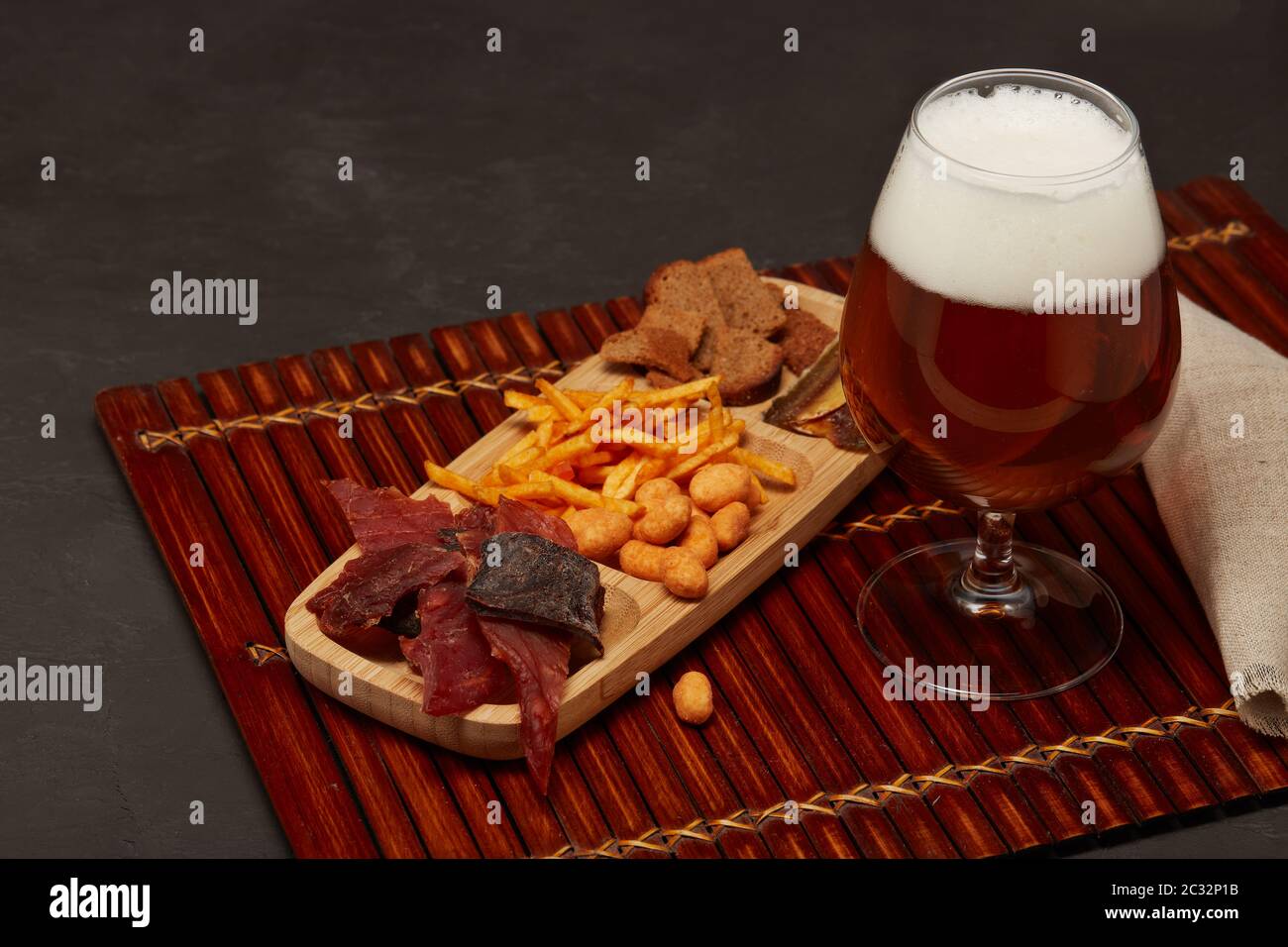 Glass with beer and set of various kind snacks: jerky, potato chips ...