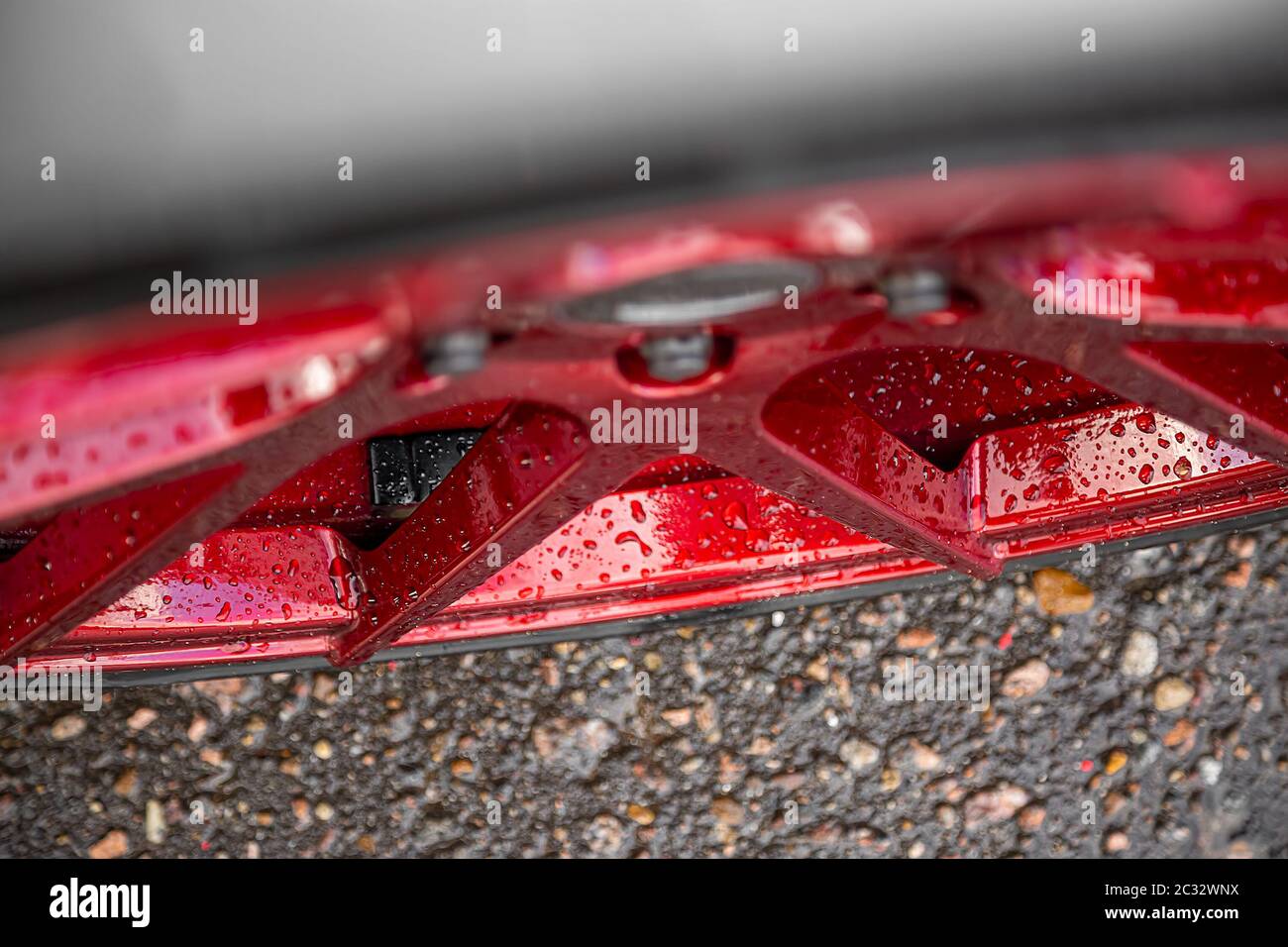 red candy colored light alloy wheels on asphalt background. In ...