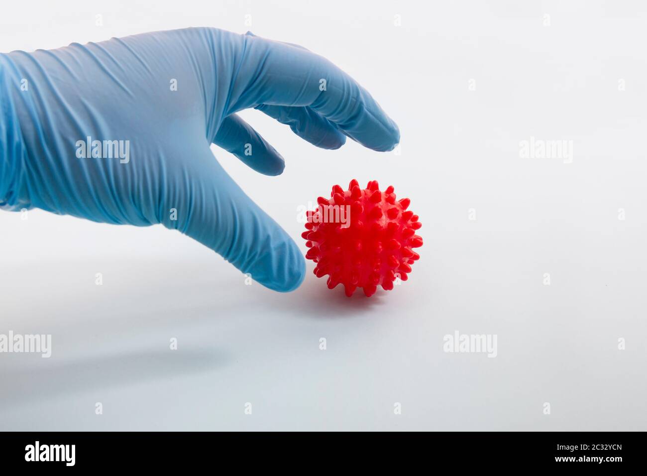 Doctor's hand holding red virus ball concept over a light blue ...