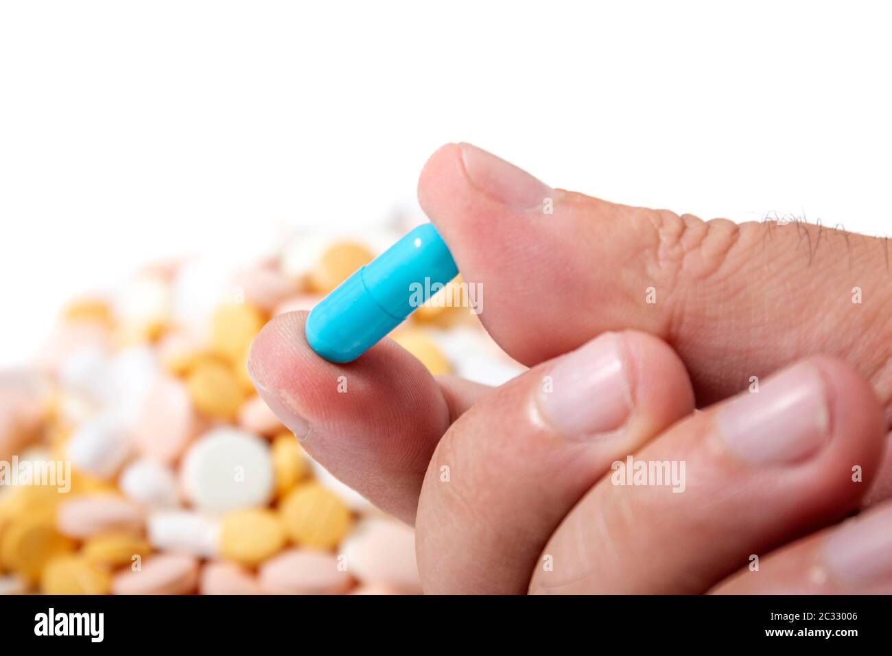 Hand holds a blue pill over a pile of other assorted mix of pills Stock ...
