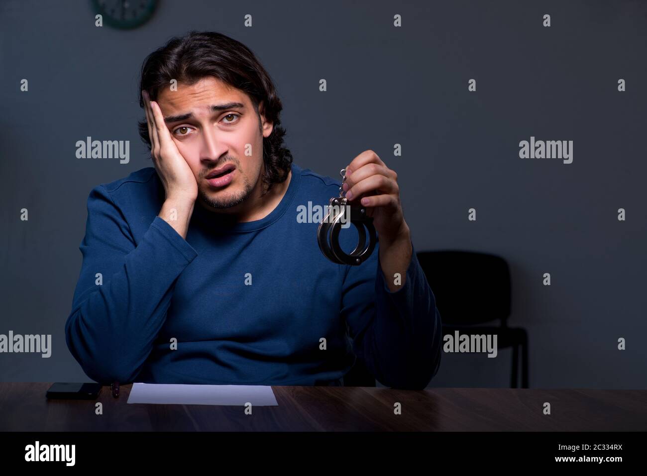 Young convict man sitting in dark room Stock Photo - Alamy