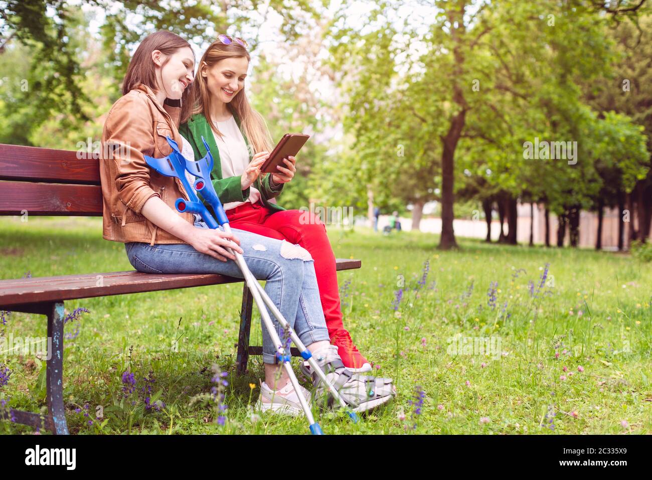 Woman spending time with her friend having a broken leg sitting on a ...