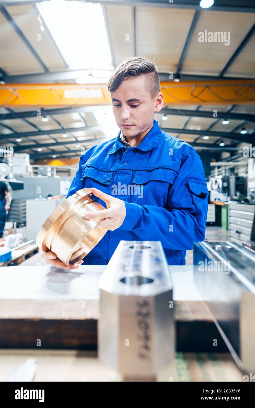 Apprentice in metalworking looking at workpiece being satisfied Stock ...