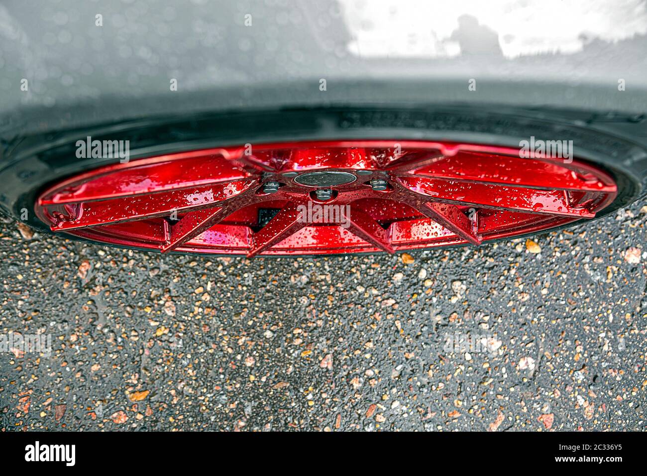 red candy colored light alloy wheels on asphalt background. In ...