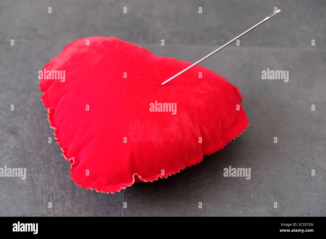 red pincushion and a large sewing needle, needle spell Stock Photo - Alamy