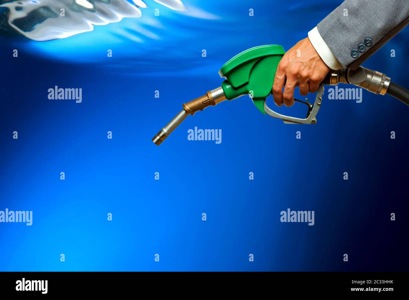 Refueling hose on blue background. Holding green color fuel gasoline ...