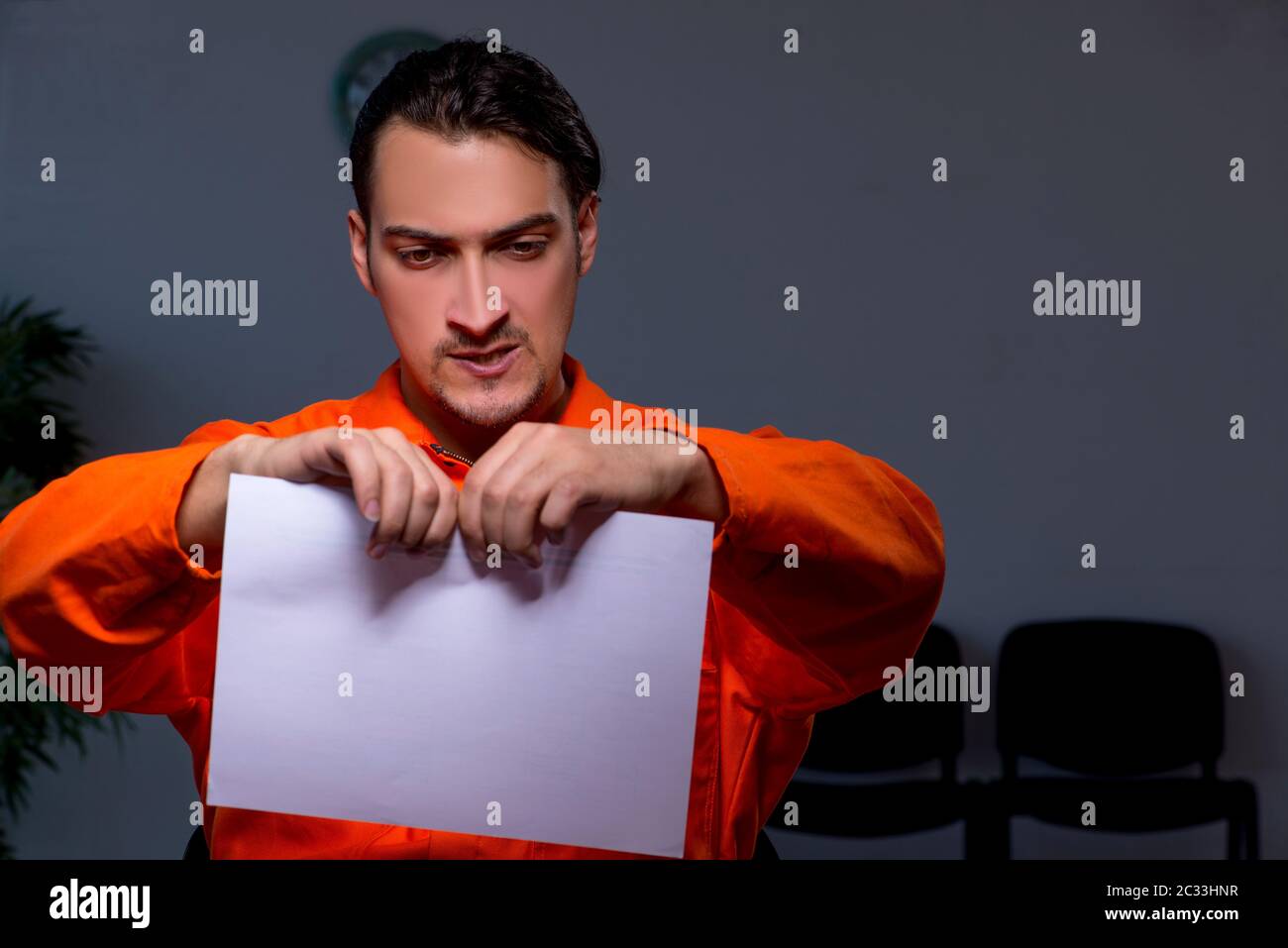 Young convict man sitting in dark room Stock Photo - Alamy